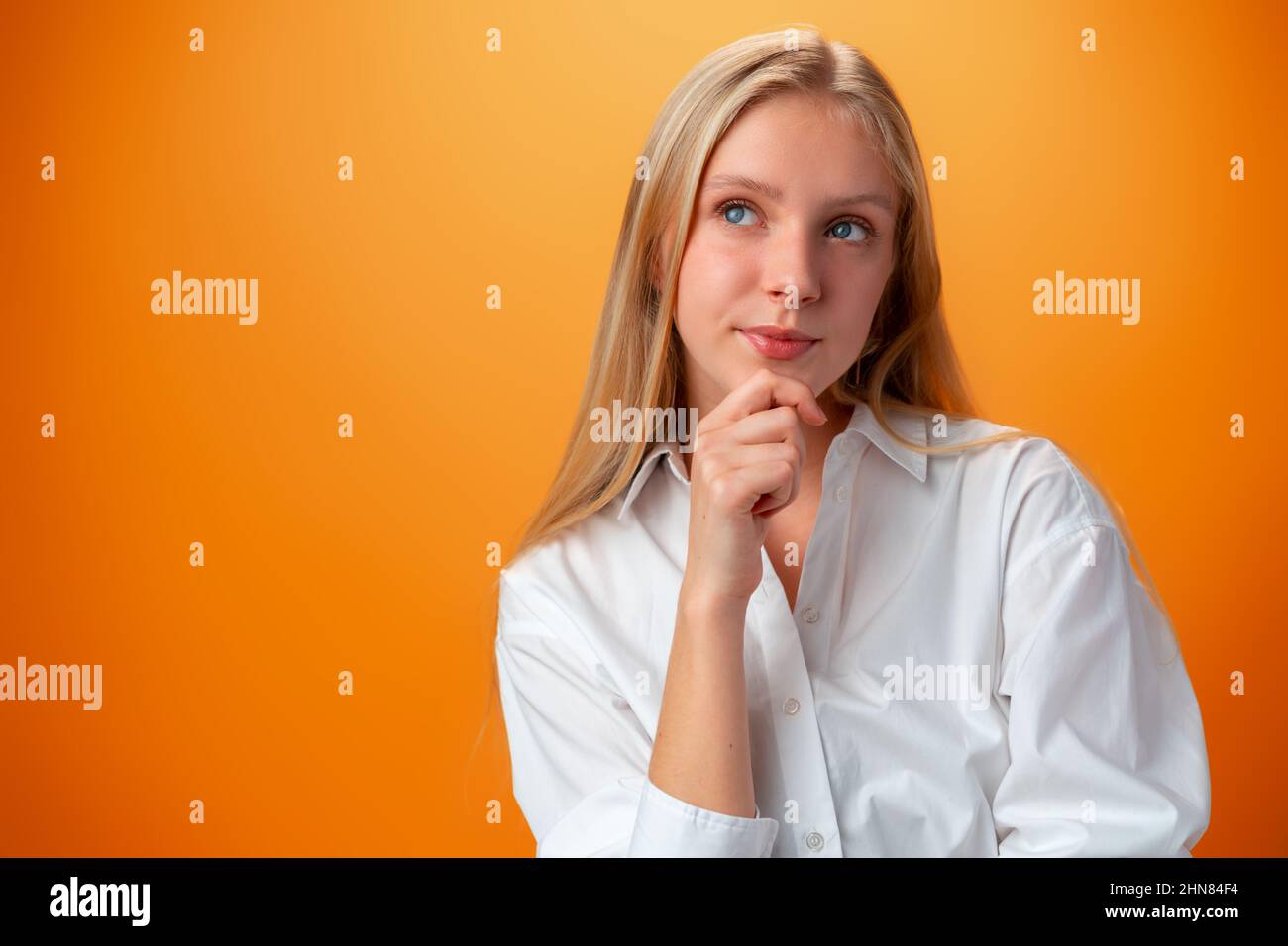 Portrait of cute thoughtful teen girl against orange background Stock ...