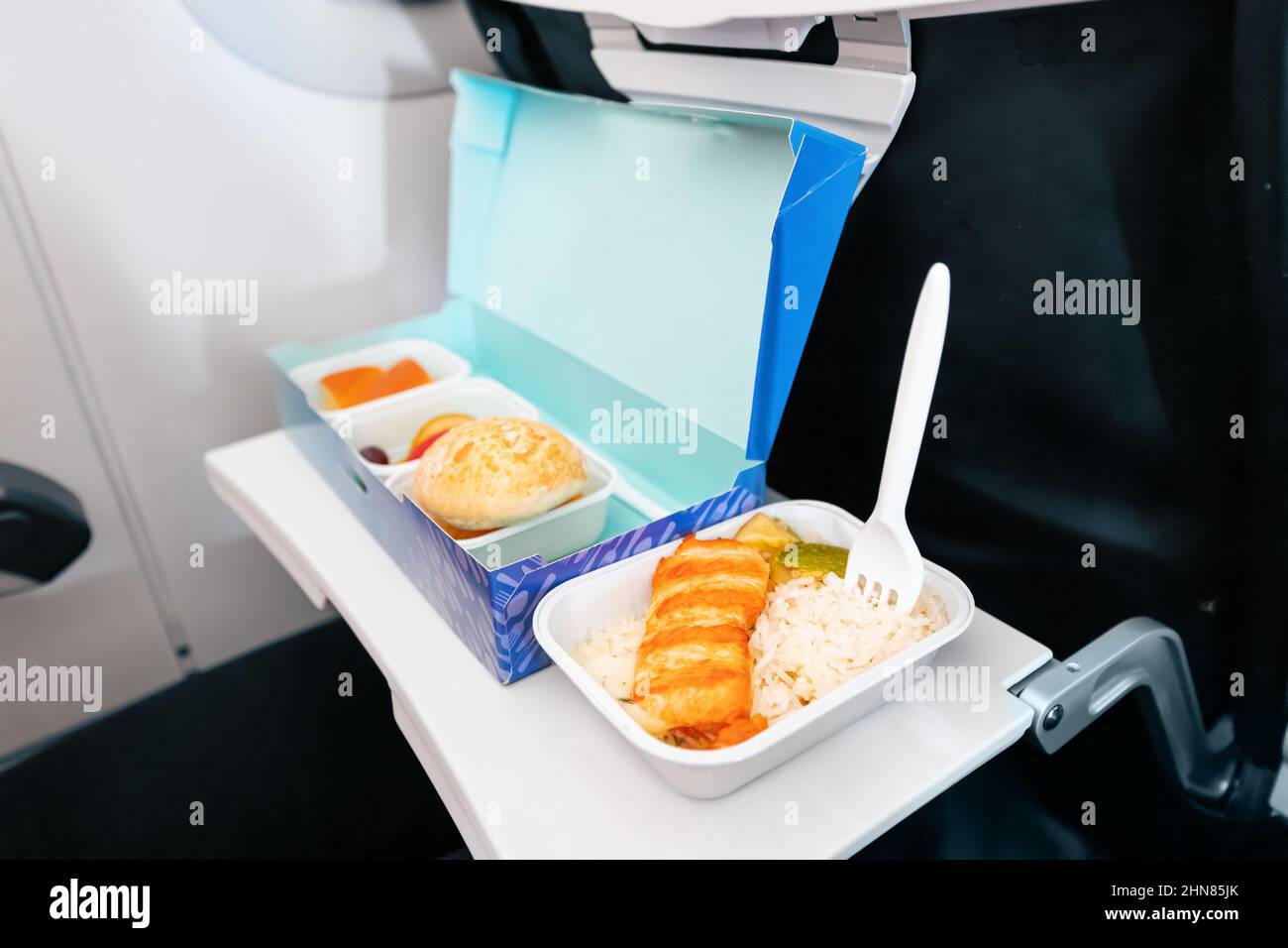 Container with healthy rice and fish dinner during the flight on board ...