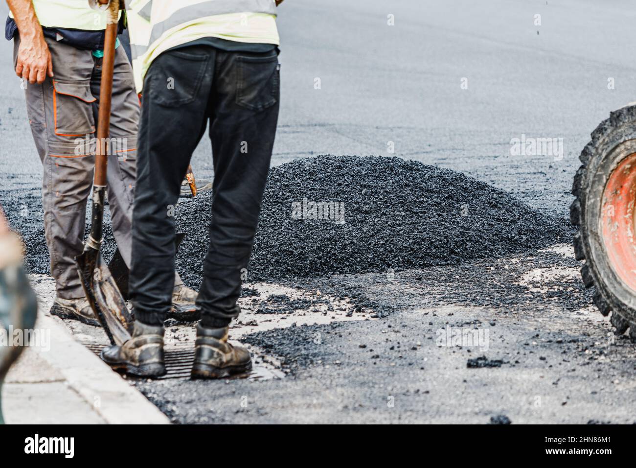 Heavy and dirty manual work on laying fresh asphalt and bitumen on a ...