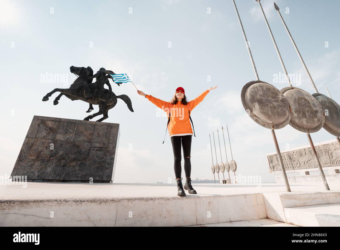Happy student girl with a Greek flag on the background of a Statue of ...