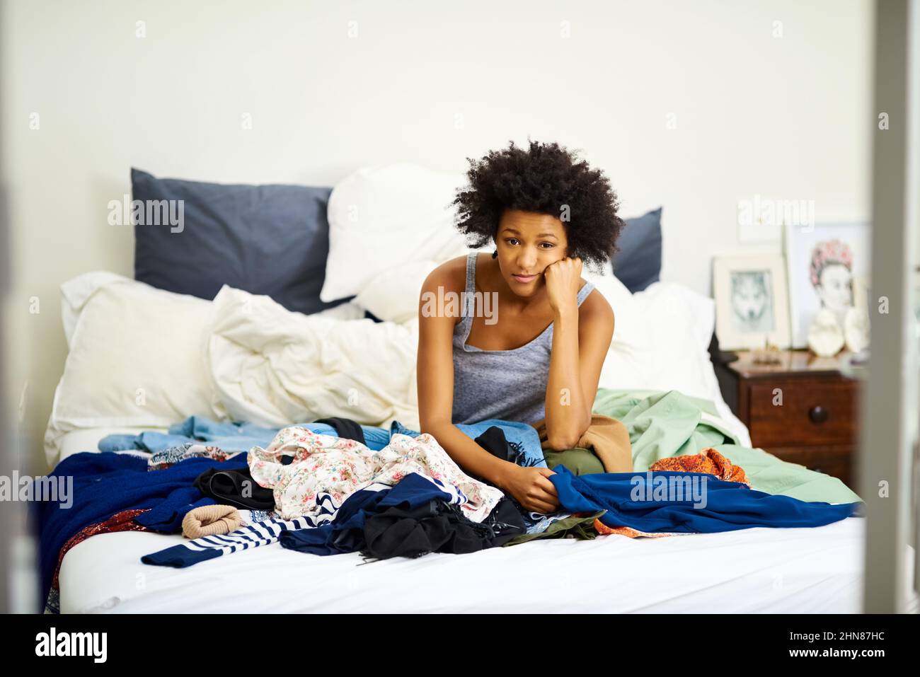 I need new clothes. Shot of an unhappy young woman getting dressed with ...