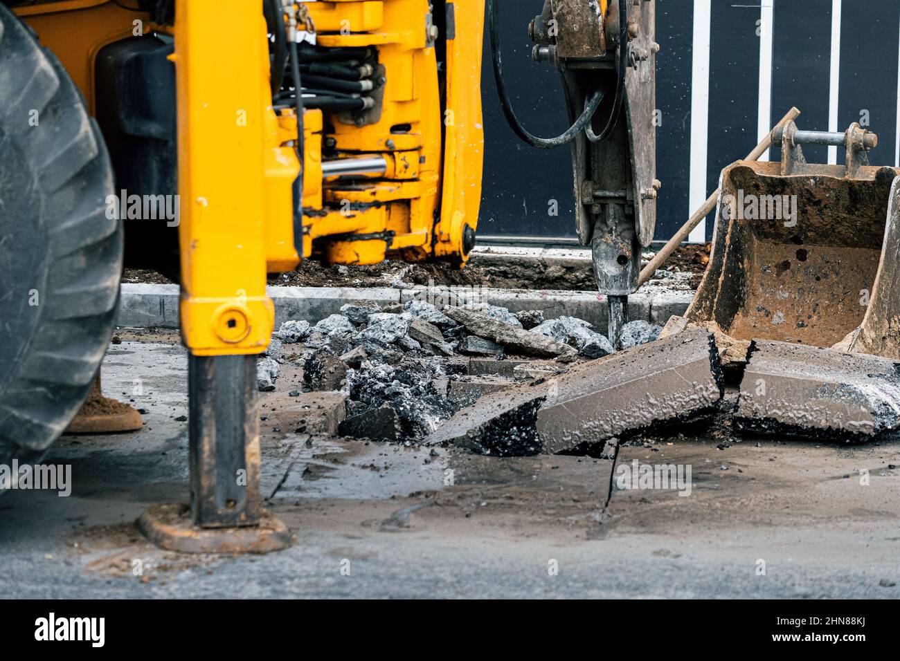 Heavy machinery removes the old layer of asphalt on a city street with ...