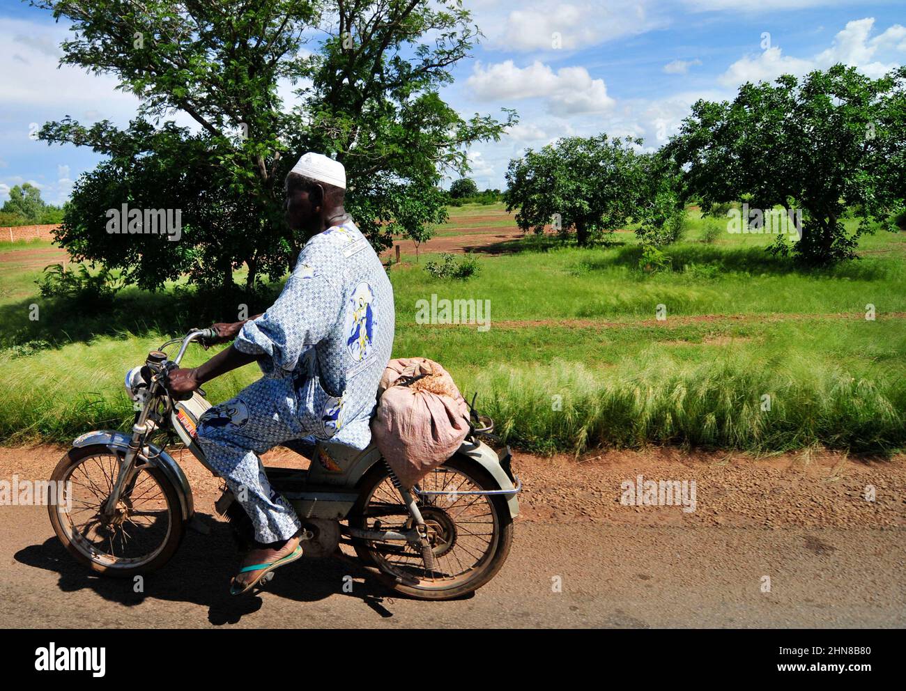 A Burkinabe Muslim man riding his motorcycle in the countryside in ...
