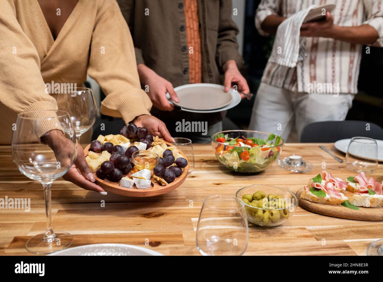Close-up of woman putting the appetizers on dining table with her ...