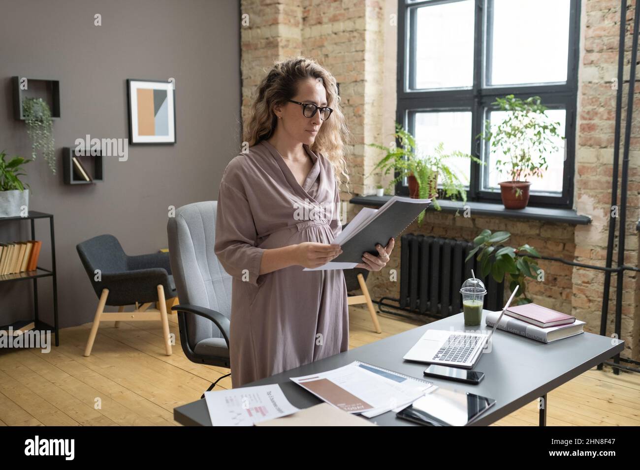 Secretary reading documents standing near the workplace at office, she ...