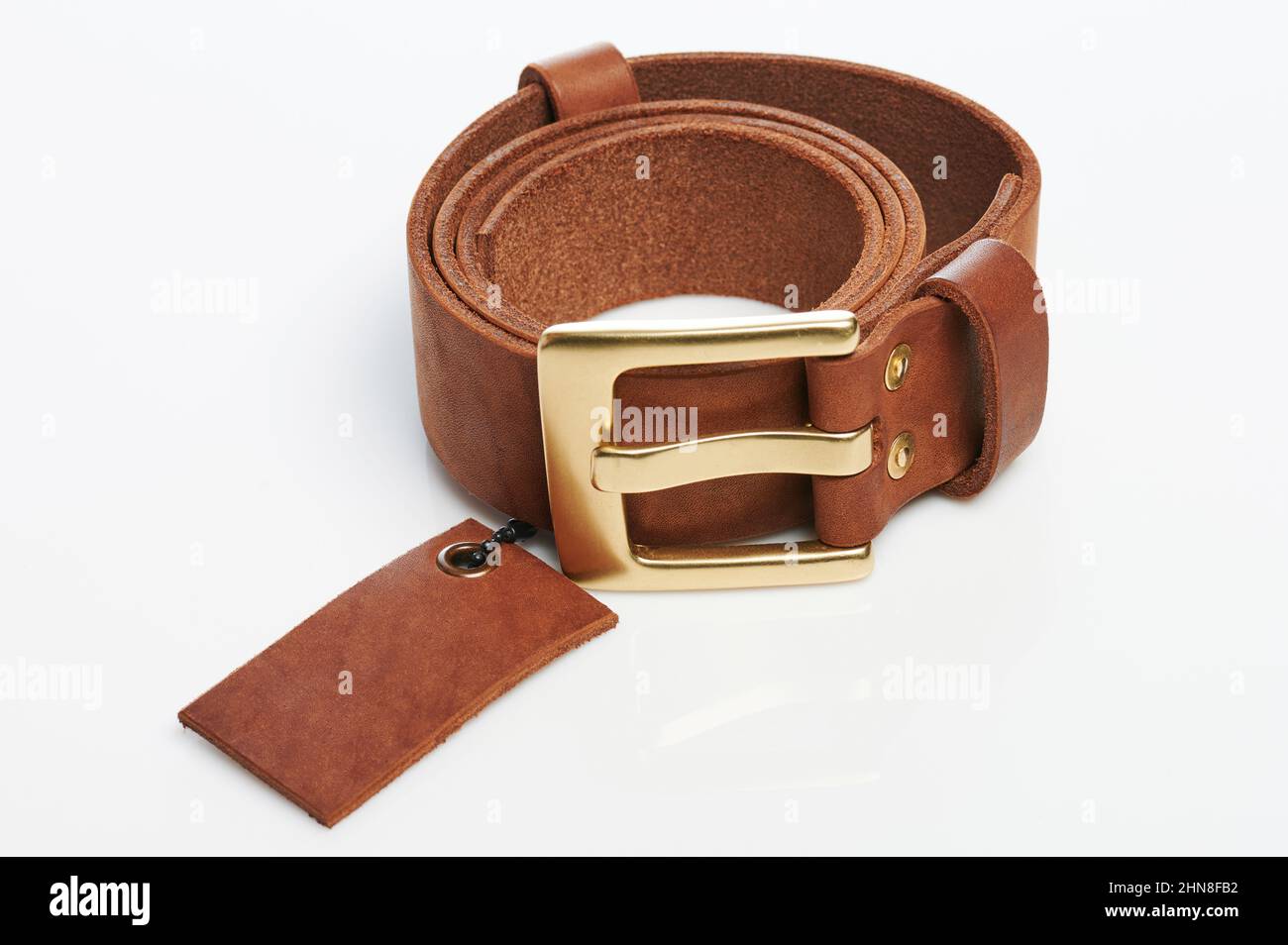 New brown color leather belt with tag rolled isolated on studio ...