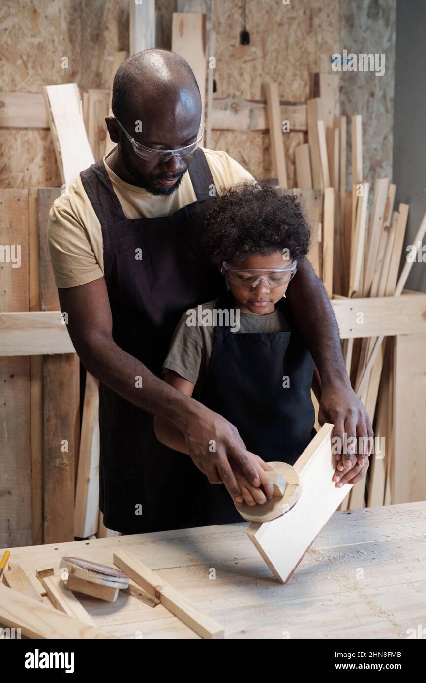 Vertical portrait of caring African-American father teaching son in ...