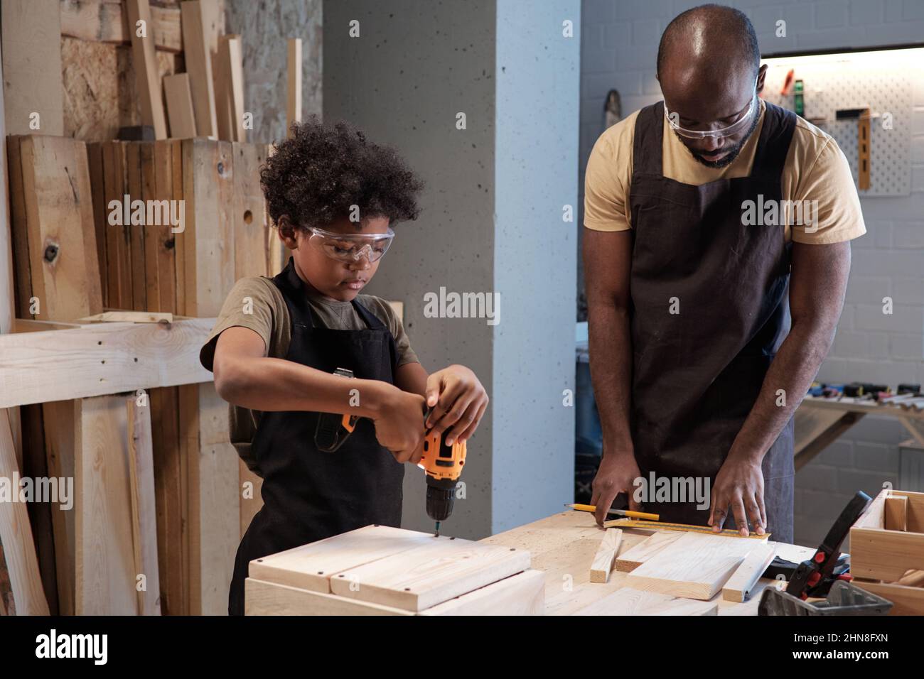 Side view portrait of cute African-American boy building wooden ...