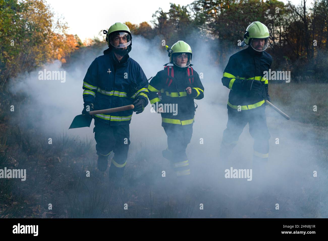 Firefighters men and woman at action, running through smoke to stop ...