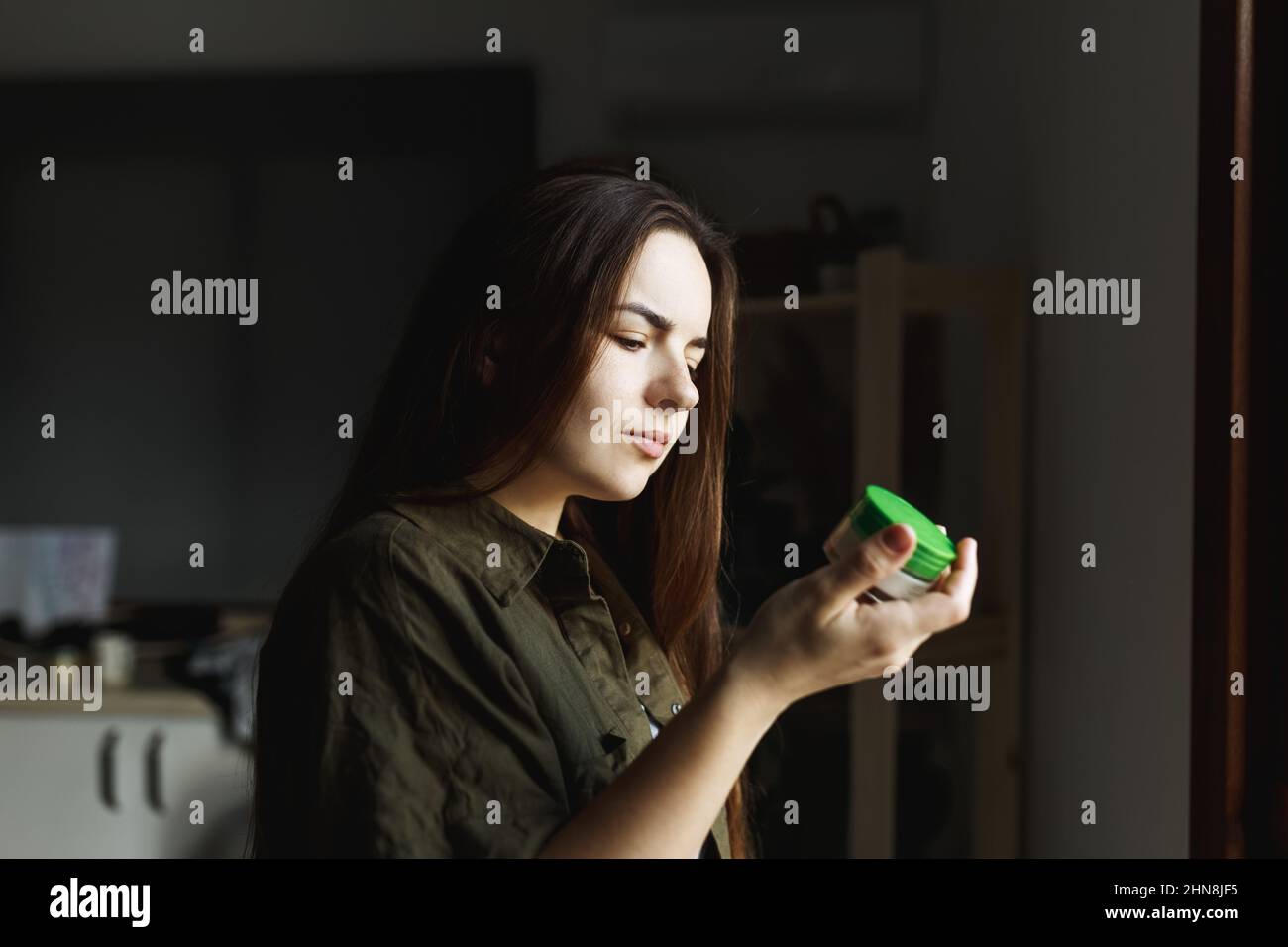 Young dreamy woman reading ingredients on package at home next to ...