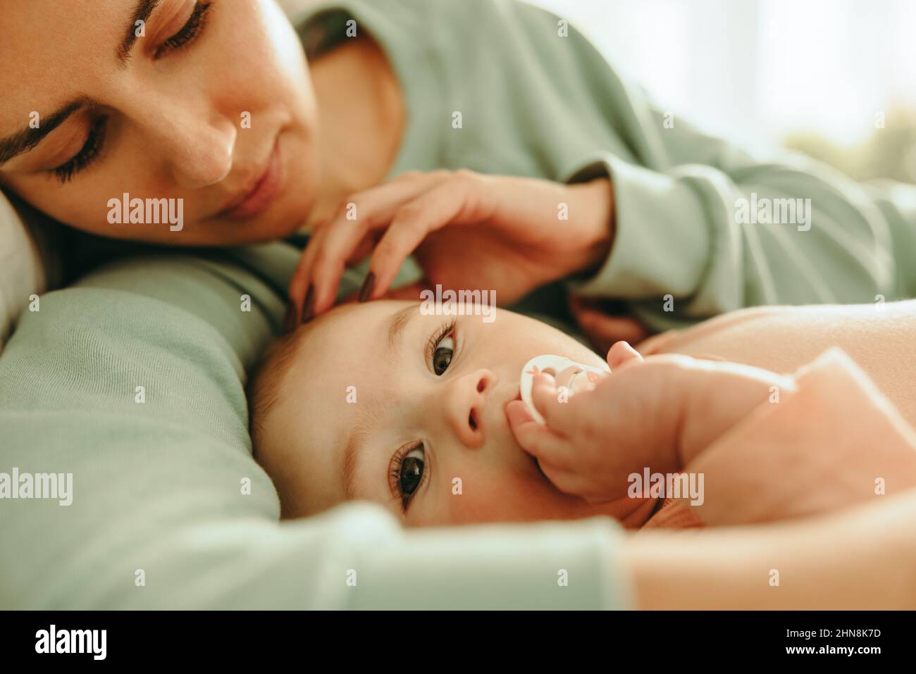 Mother cuddling her newborn baby on the bed. Closeup of an affectionate ...