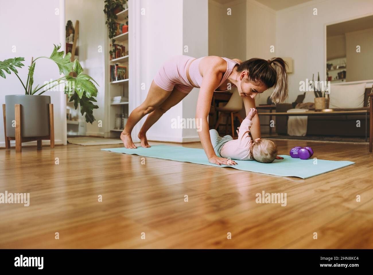 Healthy new mom working out with her baby at home. Yogi mom doing push ...