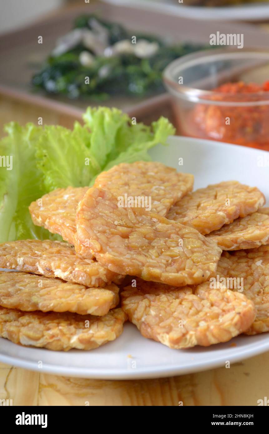 fried Tempe / tempeh in white plate,with slice lettuce as a garnish ...