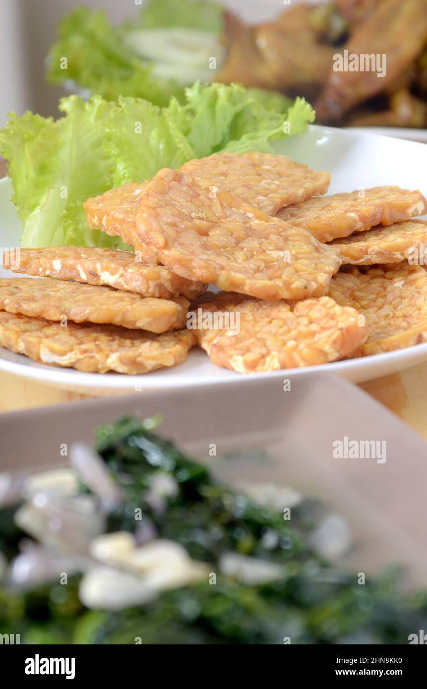 fried Tempe / tempeh in white plate,with slice lettuce as a garnish ...