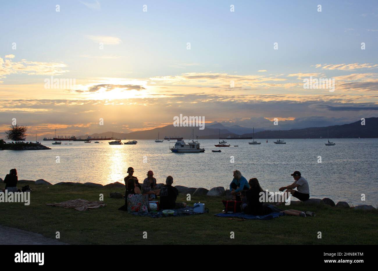 People sitting on the beach in Vancouver during the sunrise Stock Photo ...