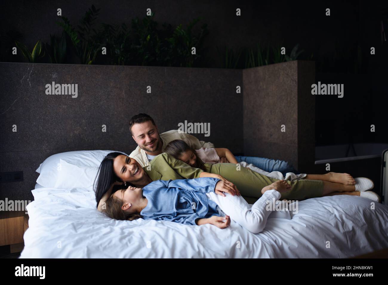 Happy young family with two children lying on bed at hotel, summer ...