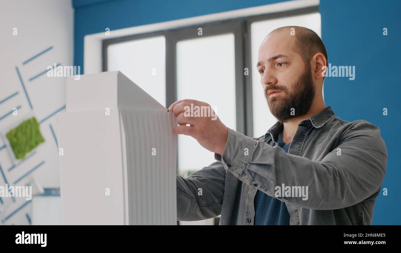 Close up of man engineer designing building model and maquette layout ...