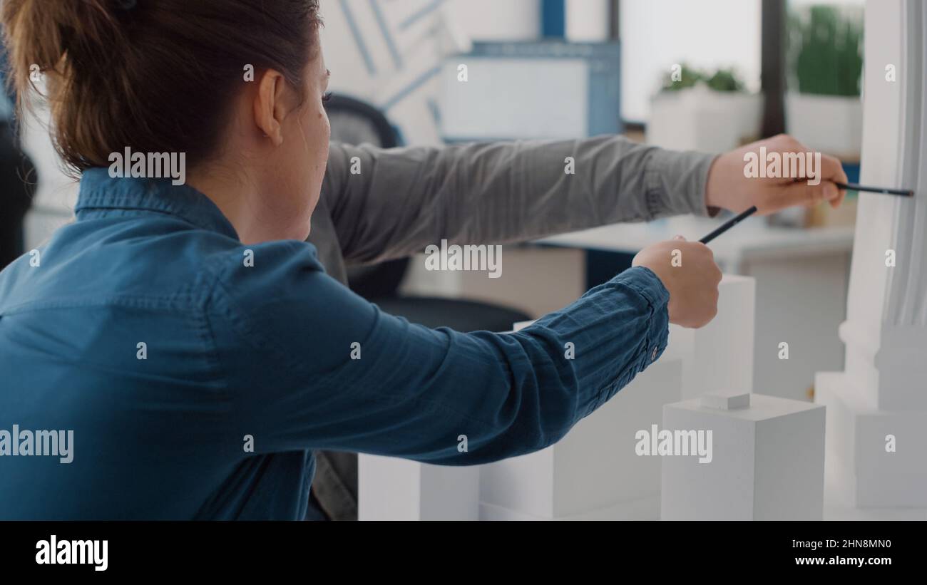Close Up Of Man And Woman Talking About Maquette Design Analyzing Blueprints Plans On Table