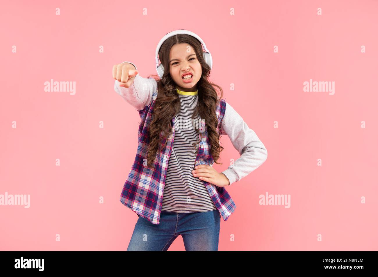 angry child listen music in headphones on pink background, back to ...