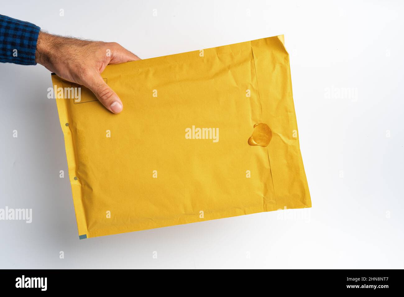 Male hand holding parcel post against white background Stock Photo - Alamy