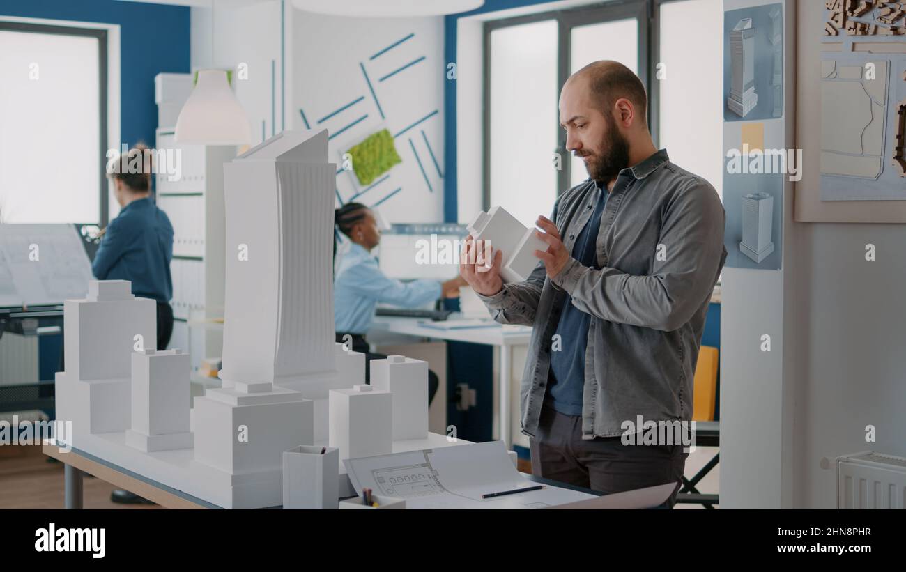 Man engineer designing blueprints plans of construction with building ...