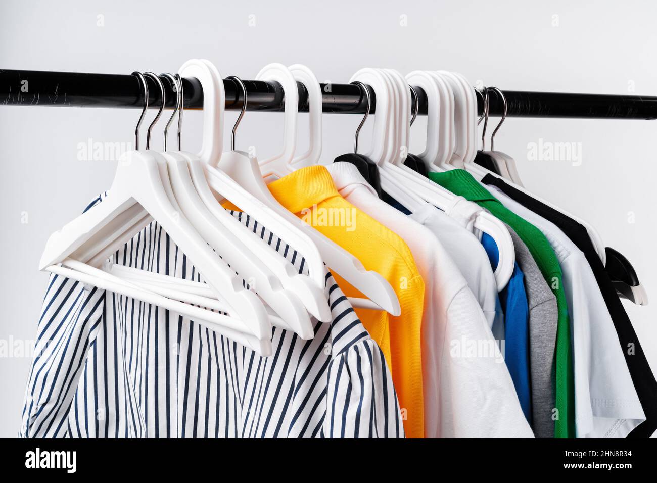 Clothes hang on clothing rack over white background Stock Photo - Alamy