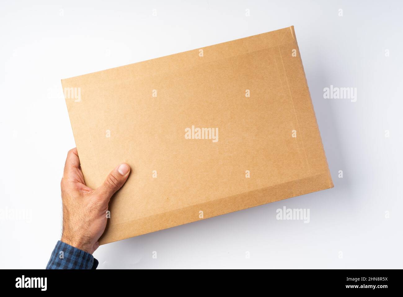 Male hand holding parcel post against white background Stock Photo - Alamy