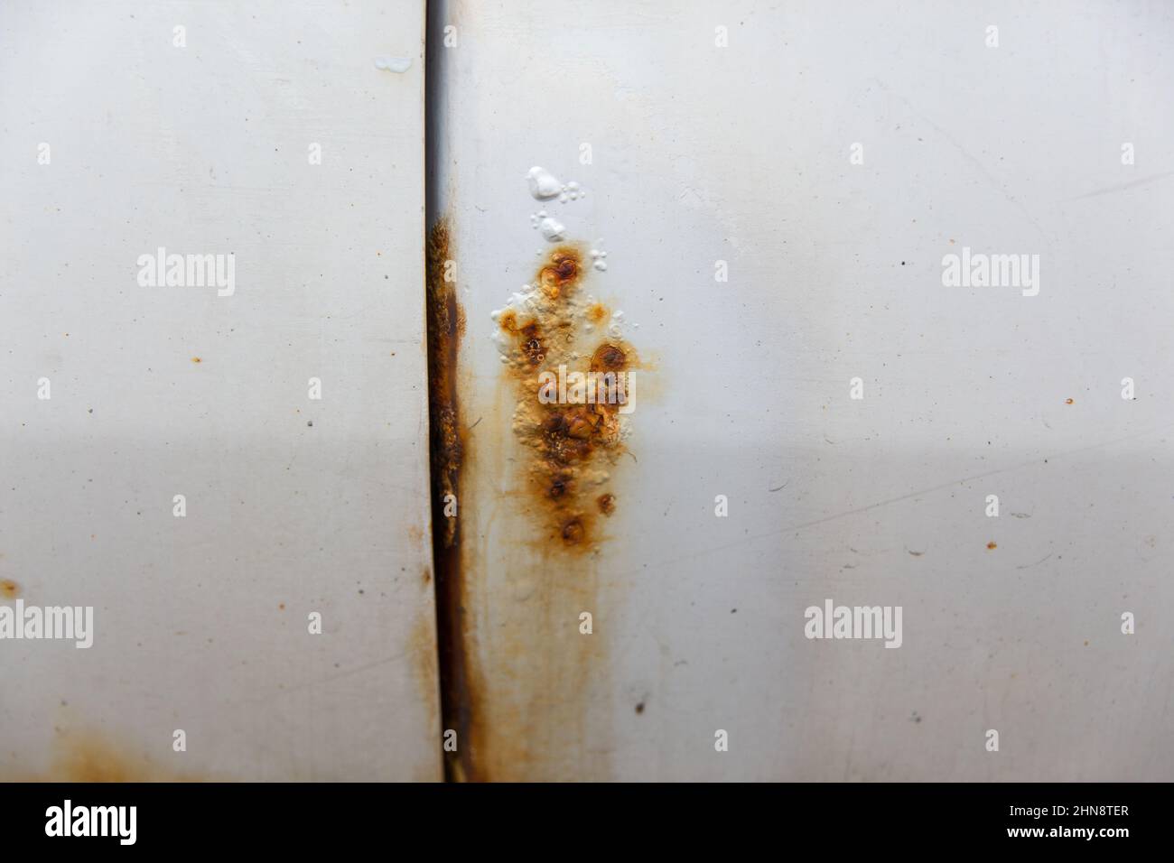 Rust on the side of white old car. Rust hole on old worn painted metal ...