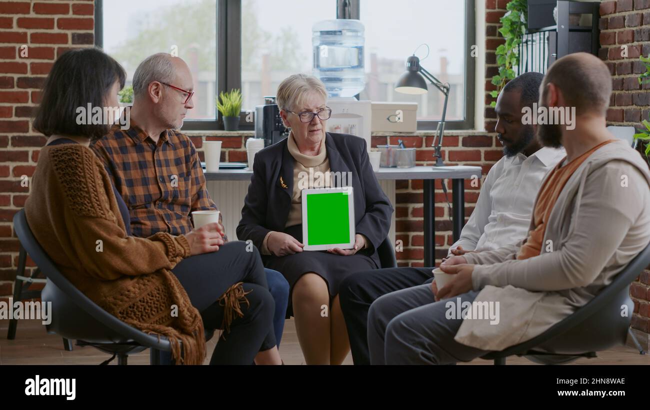 Psychotherapist and patients looking at green screen on digital tablet ...