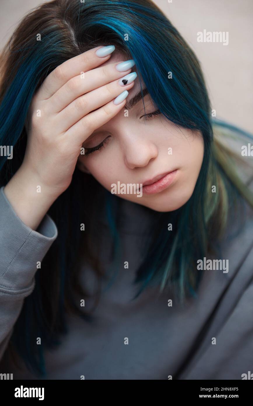 A teenage girl with blue hair is sad and depressed. Adolescent ...