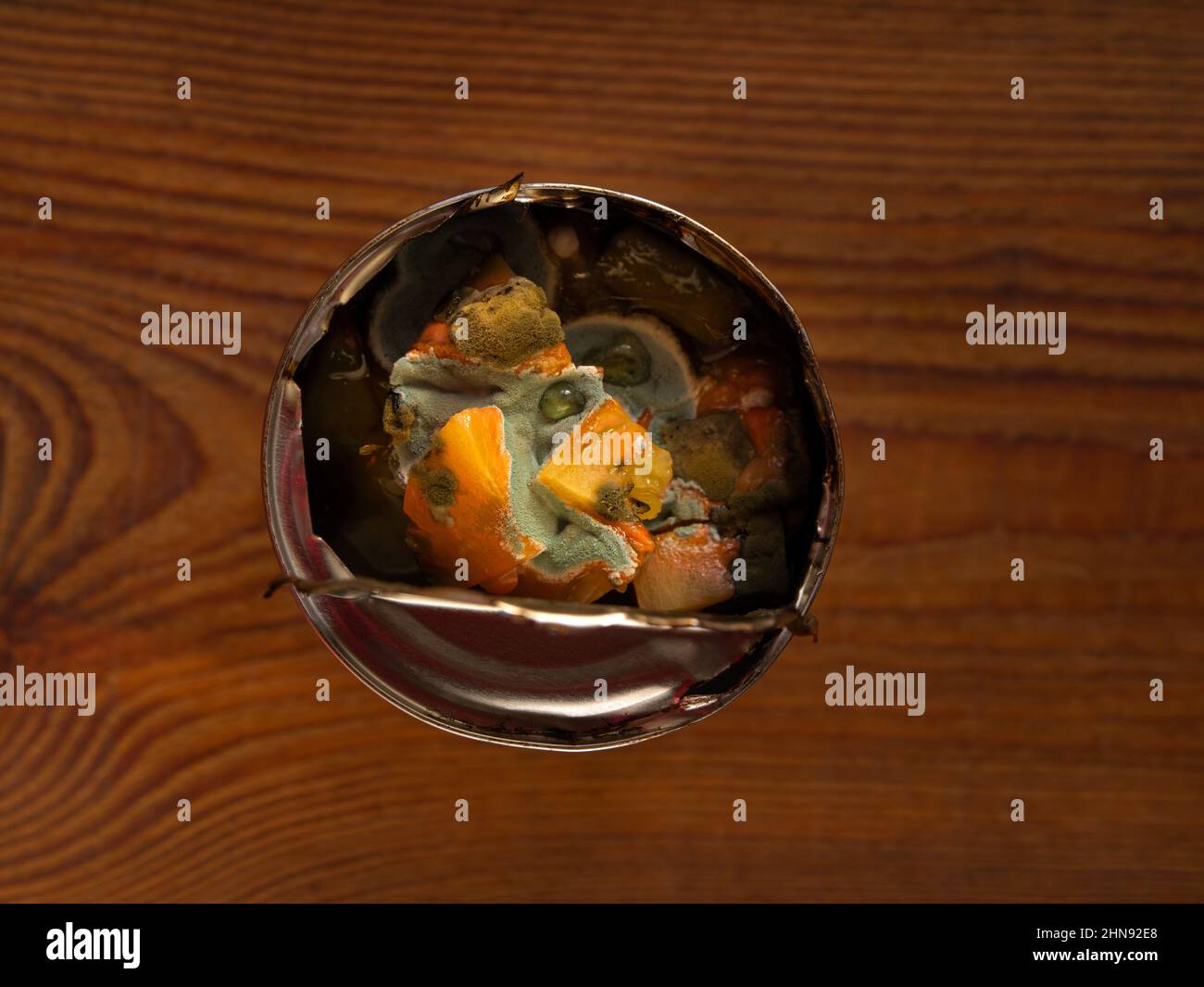 Crushed pineapple in juice with colorful green mold on wooden ...