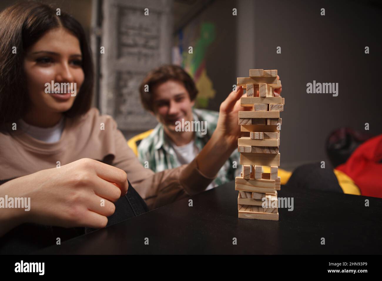 Selective focus on stacked wooden bloks, young couple enjoying playing ...