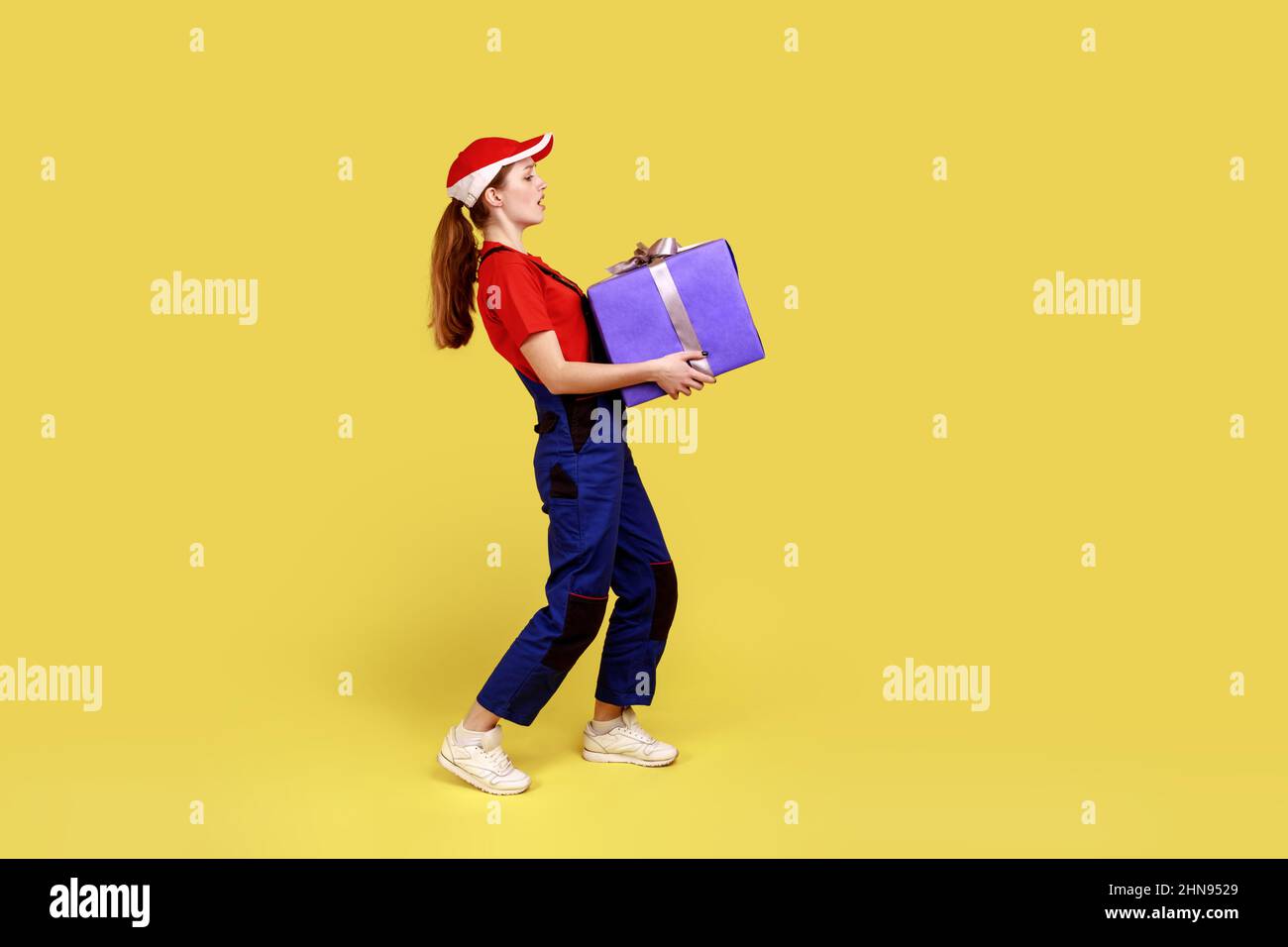 Side view portrait of courier woman carrying heavy presents boxes for ...