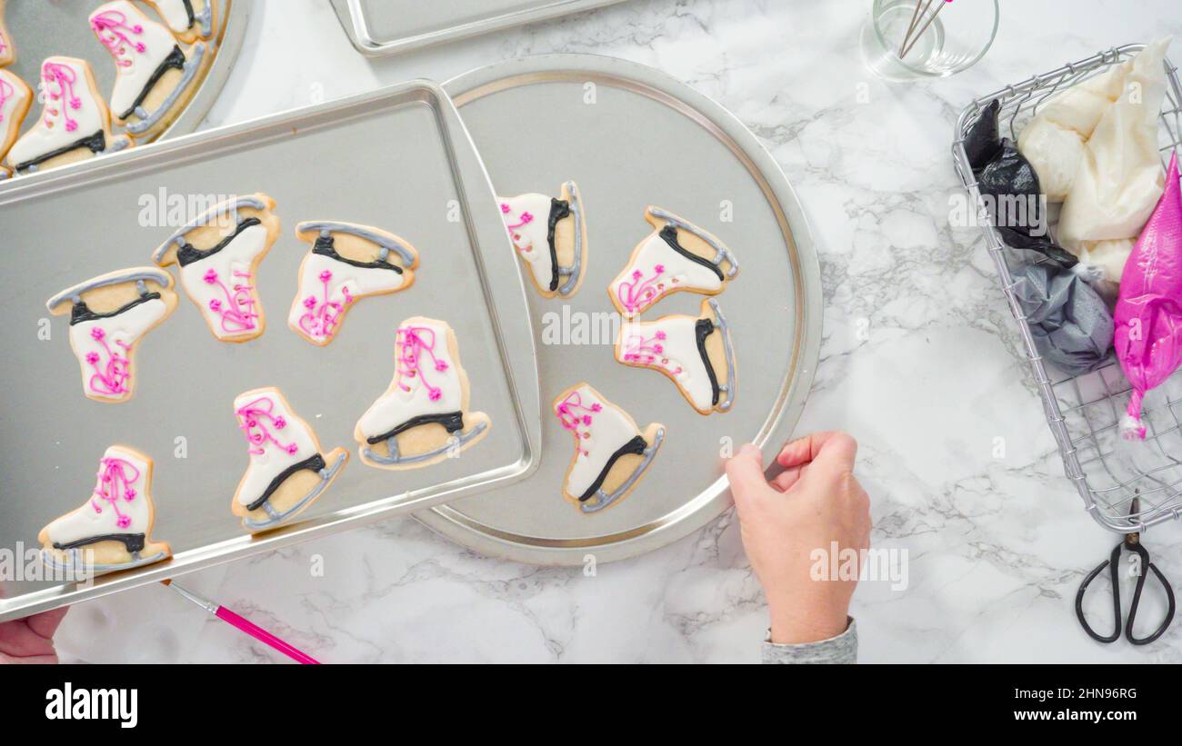 Flat lay. Brushing edible glitter on iced figure skate sugar cookies ...