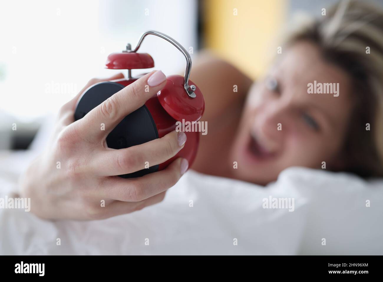 Screaming woman in bed with a red alarm clock in her hand Stock Photo ...