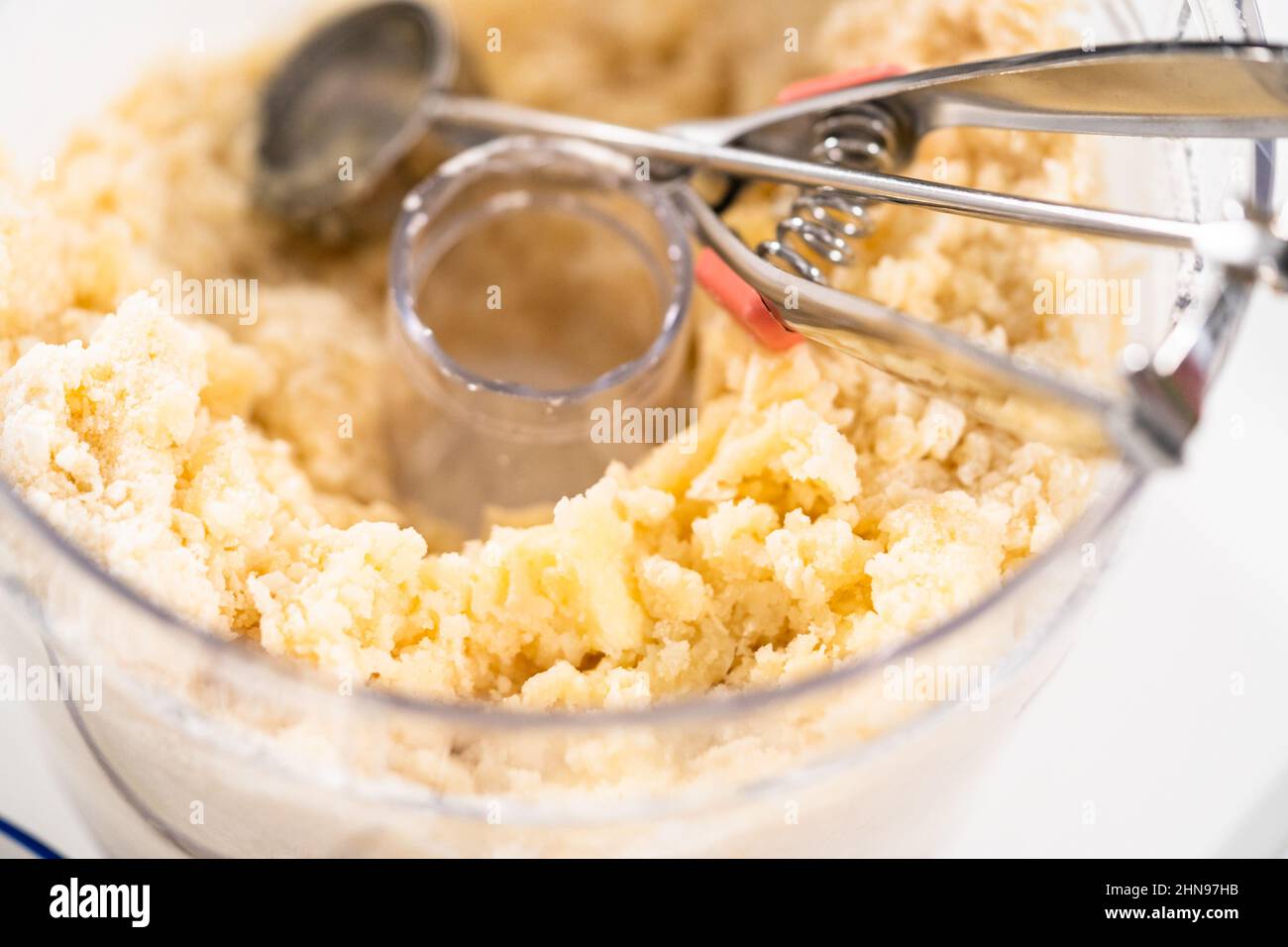 Scooping dough with dough scoop and after rolling in coconut flakes to ...