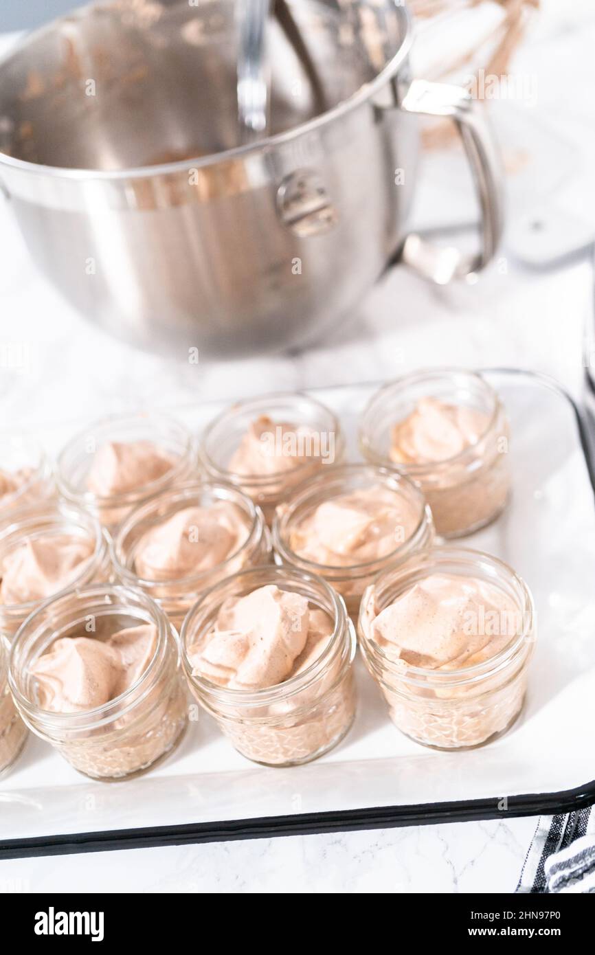Scooping mixture into the small glass jars to make homemade chocolate ...