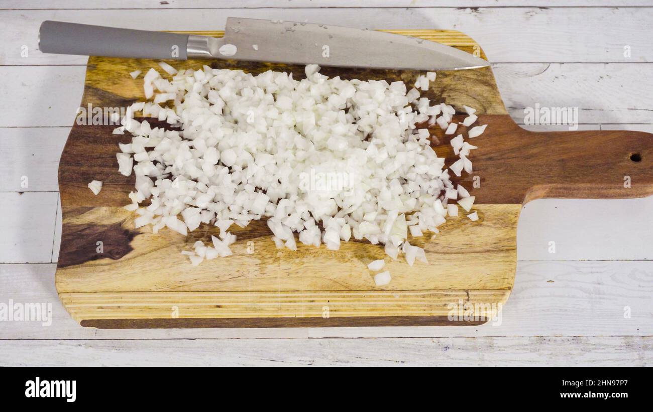 Mincing organic yellow onion on a wood cutting board Stock Photo - Alamy