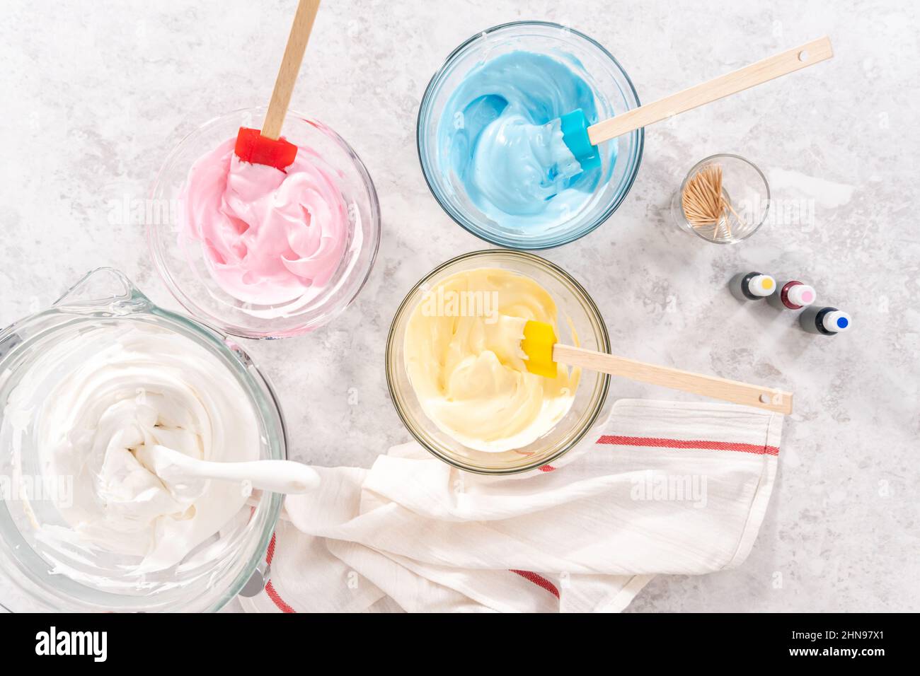 Flat lay. Mixing in food coloring into the meringue to prepare unicorn ...