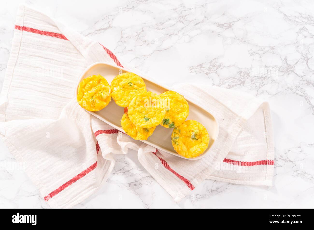 Flat lay. Bacon and cheese egg muffin on a white serving plate Stock ...