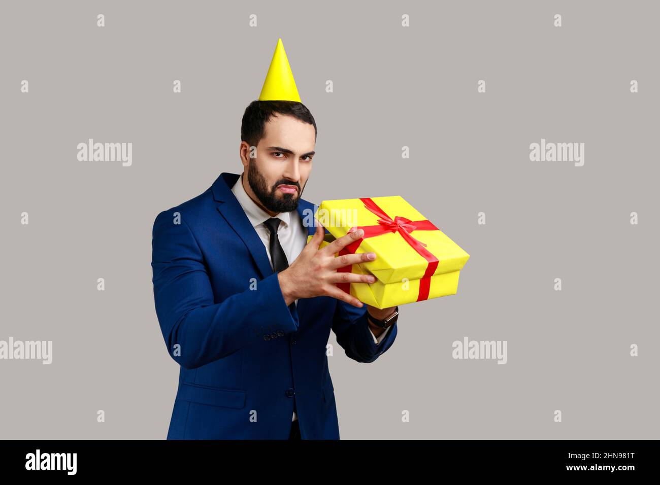 Upset man in party cone opening gift box and looking inside with ...
