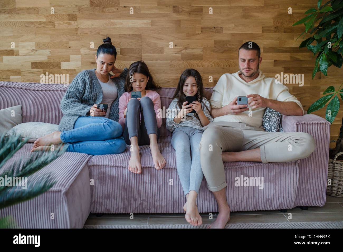Family with two little daughters, everyone is using mobile phone in the ...