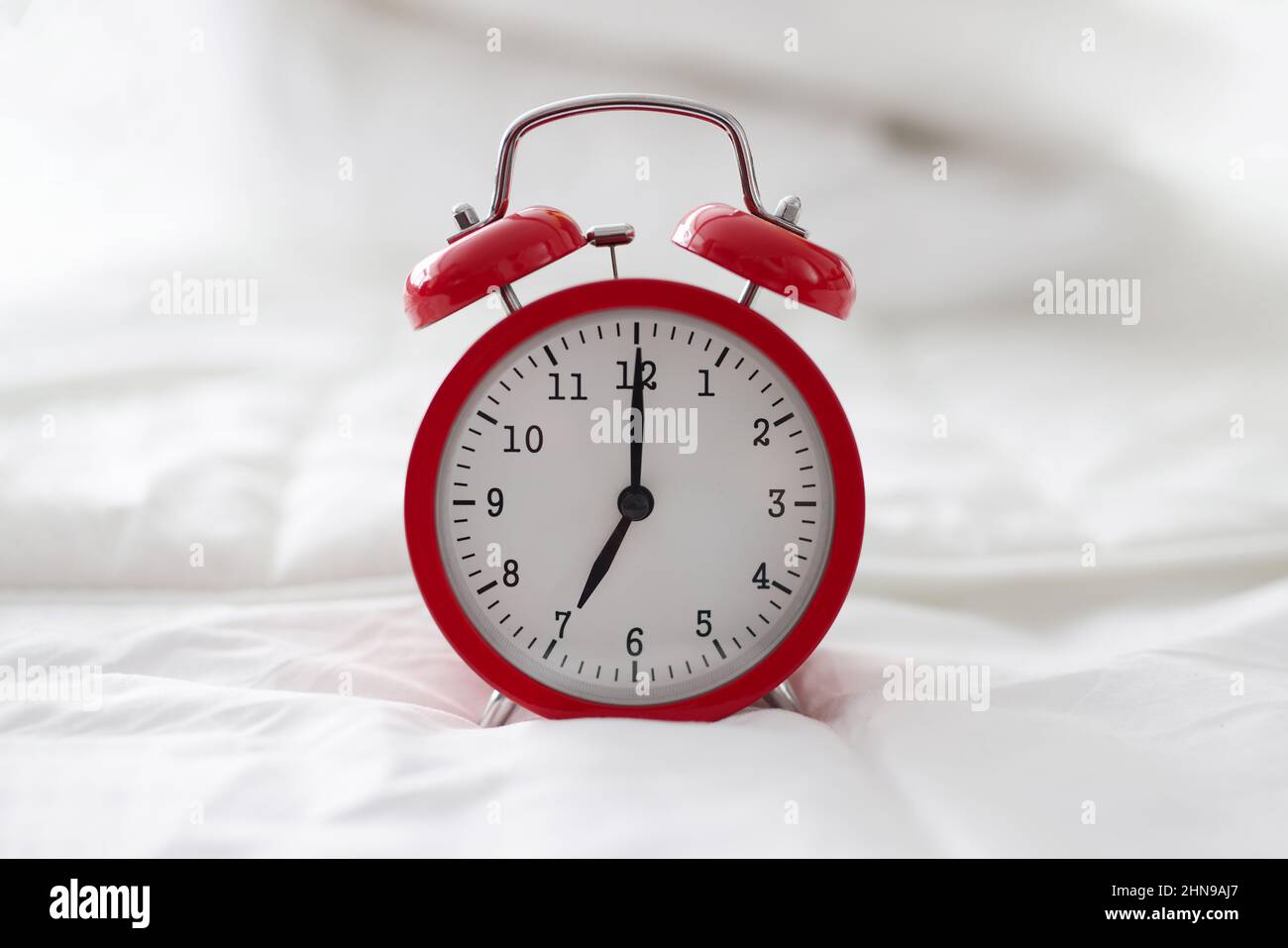 Red alarm clock on a white blanket, close-up Stock Photo - Alamy
