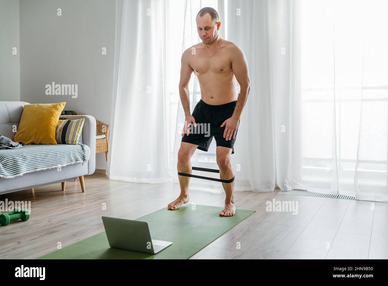 Fit sporty healthy man on a gym mat using rubber resistance exercise ...
