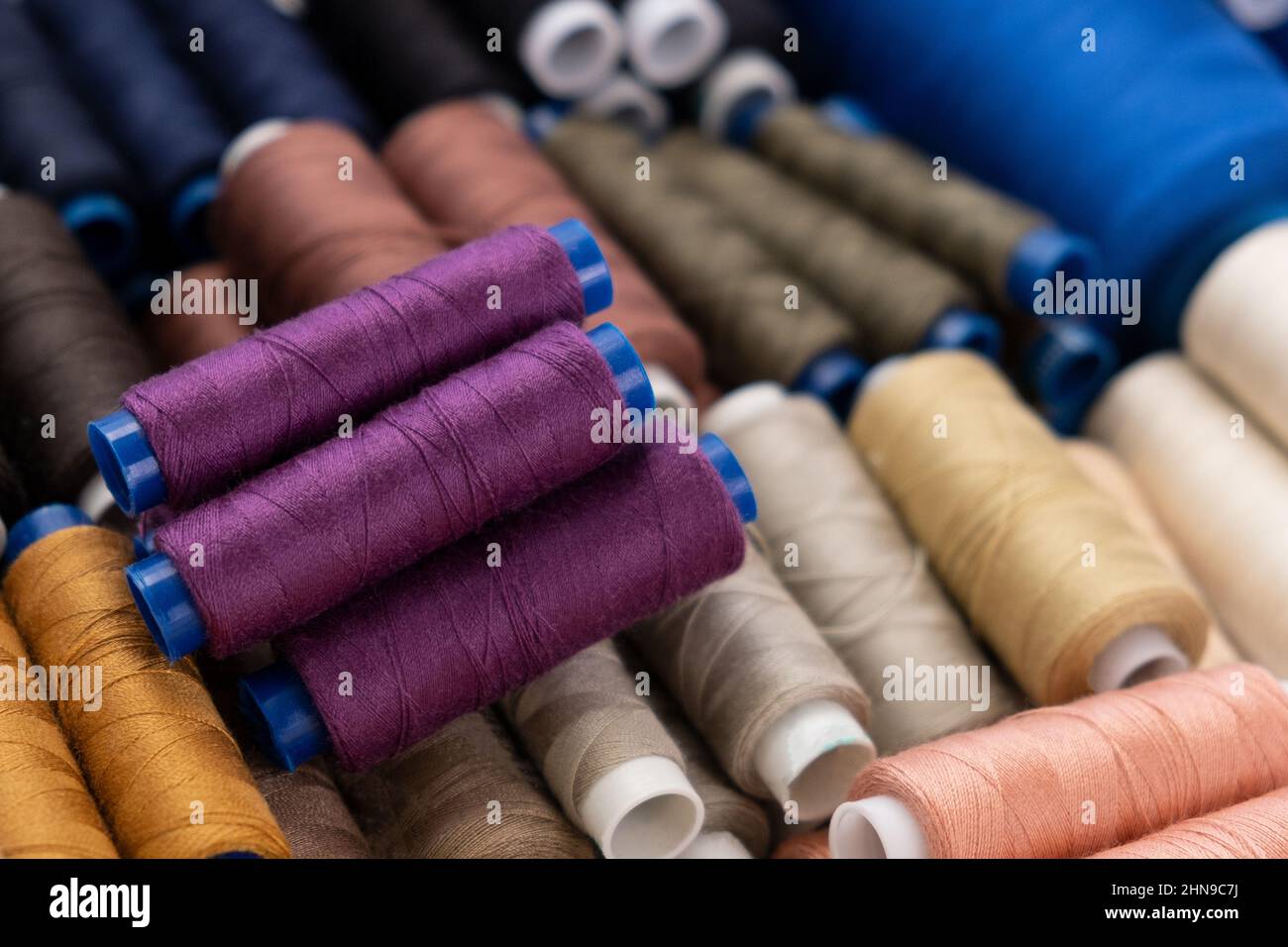 Multi-colored sewing threads laid out in a row. Bright background ...