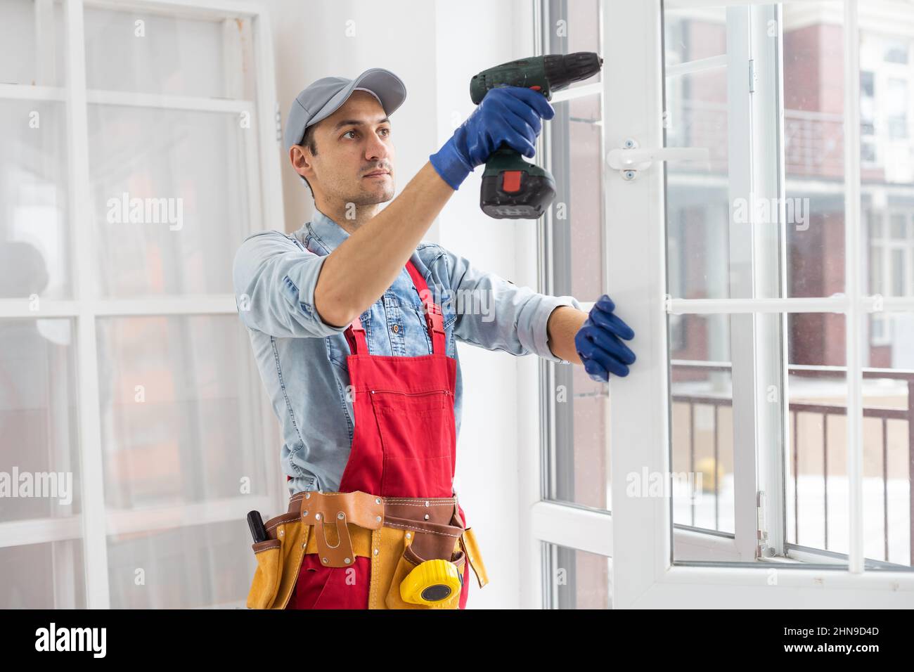 handyman adjusting white pvc plastic window indoors. worker using ...