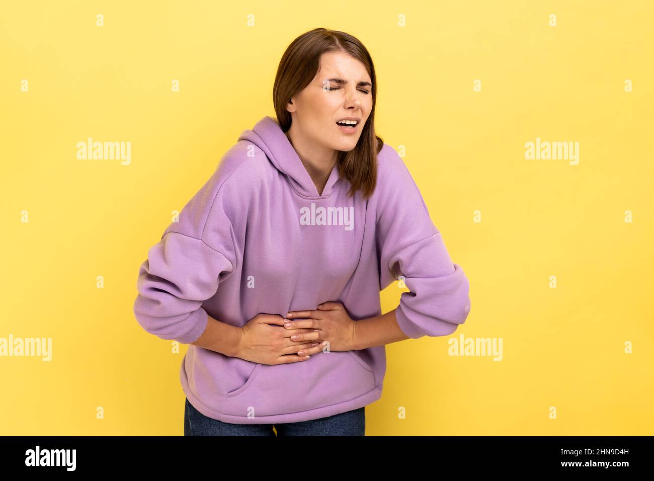 Portrait of unhealthy distressed woman clutching her belly, grimacing ...