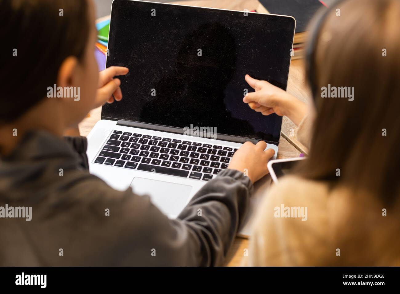 Pretty teen girl point to laptop screen and her younger sister look ...