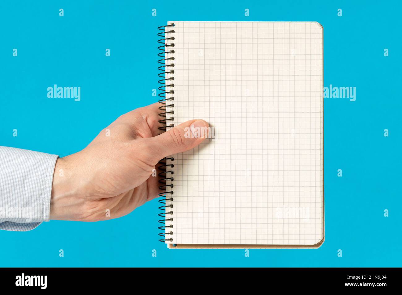 Man hand holding a notebook with square grid. Blank sheets for text ...