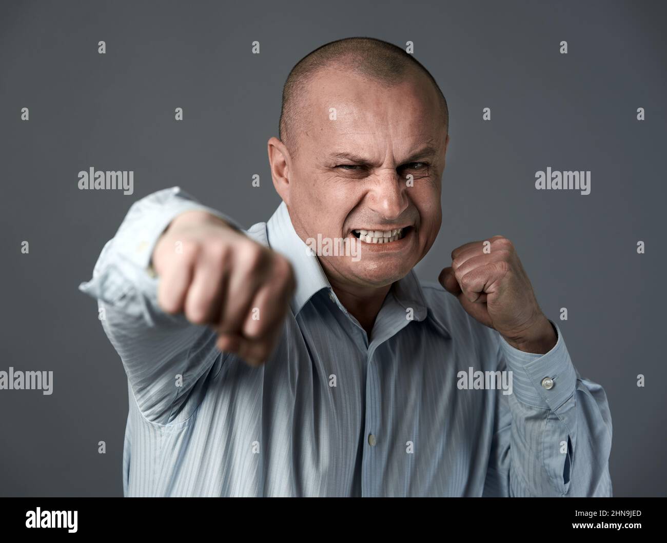 Angry businessman punching towards the camera in a rage, isolated on ...